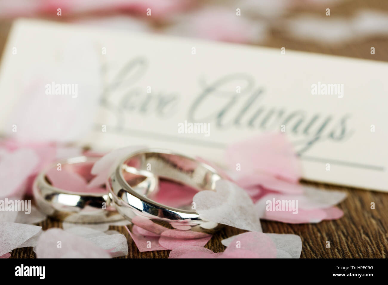 pair of white gold wedding rings on a wooden background with confetti ...