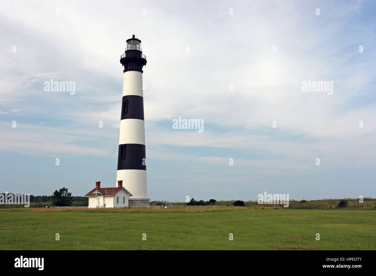 A striped lighthouse sits in a grass field Stock Photo - Alamy
