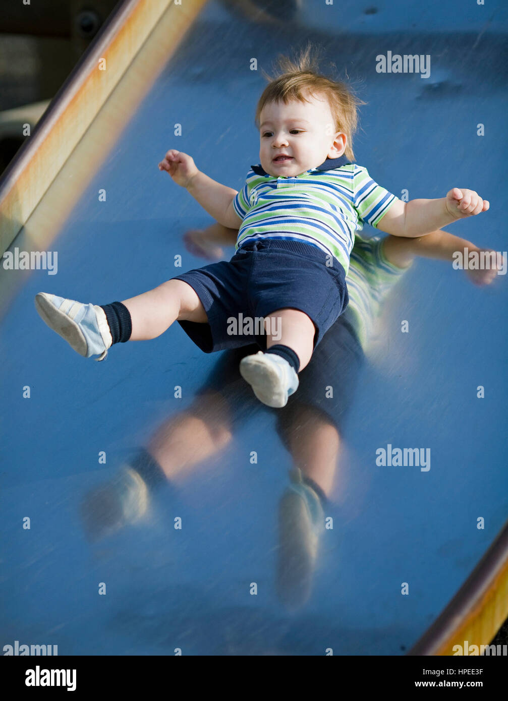 1 year old boy sliding down a playground slide Stock Photo - Alamy