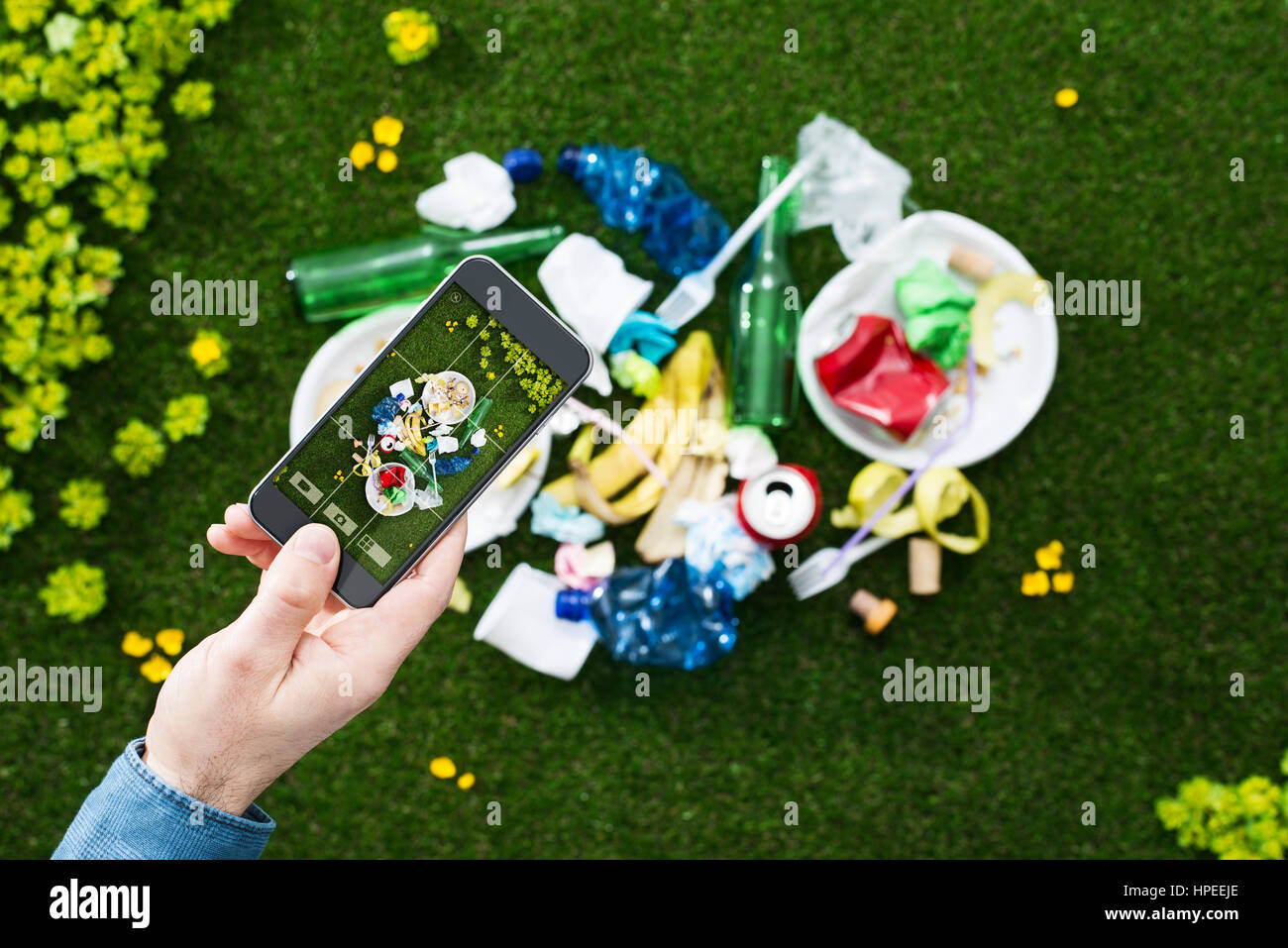 Man taking a picture of a load of garbage on the grass using a ...