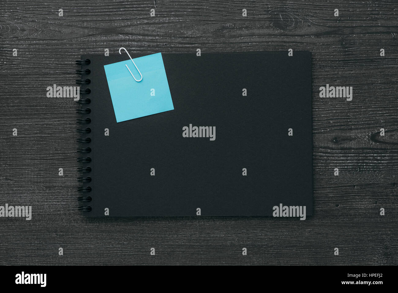 Blank dark notebook with blue memo note, planning and reminders concept ...