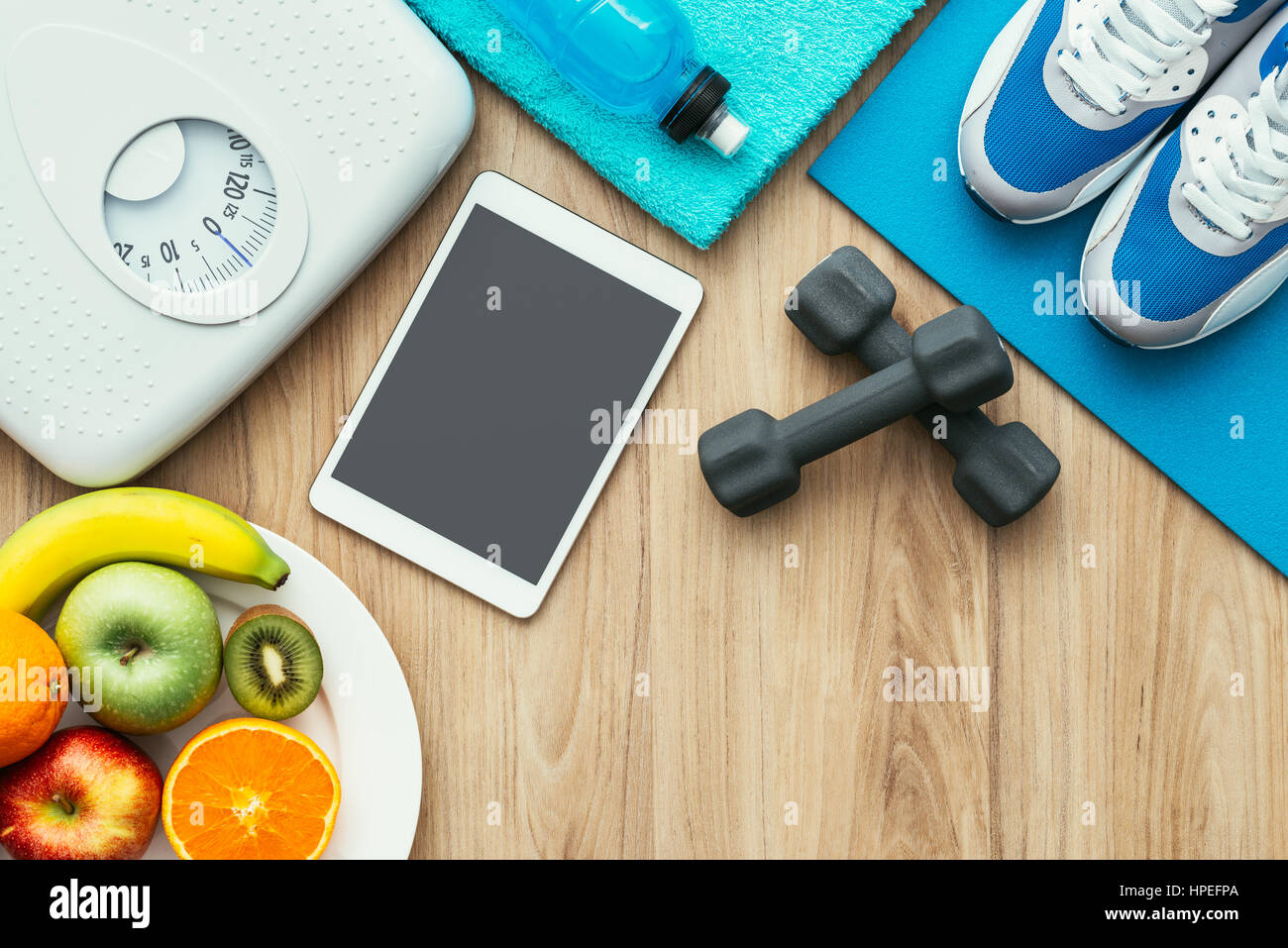 Sports and workout equipment, digital tablet and fruit on a wooden ...