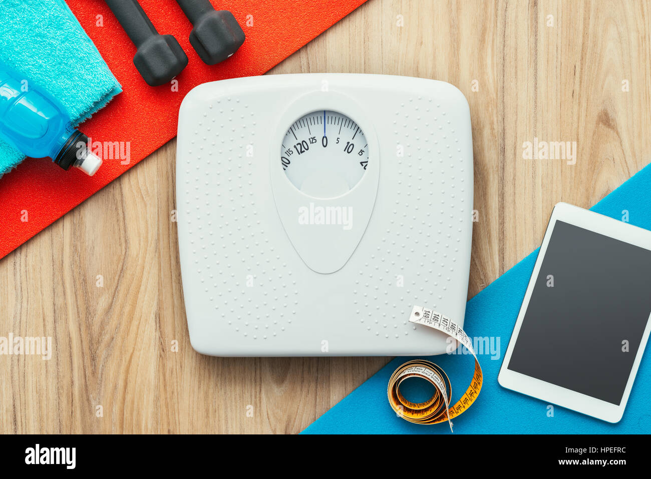 Weight scale, digital tablet and sports training equipment on a table ...