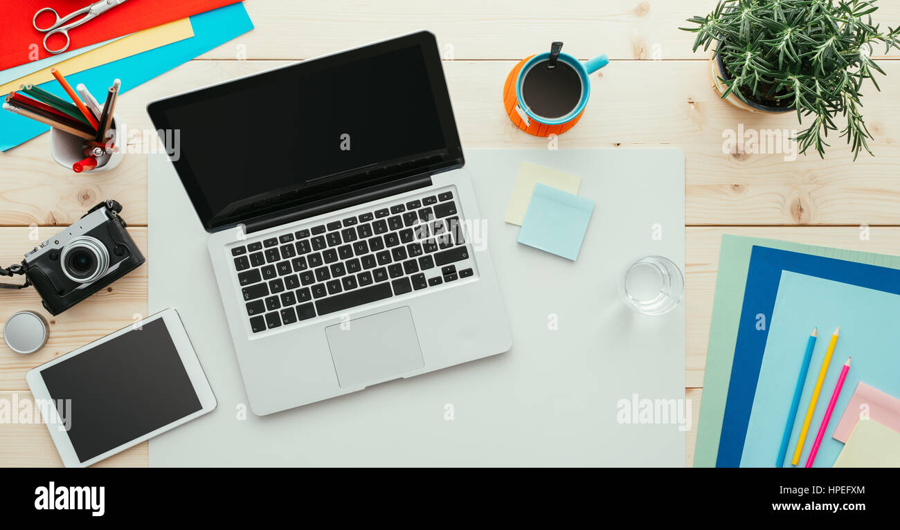 Creative contemporary desktop with laptop, digital tablet, camera and ...