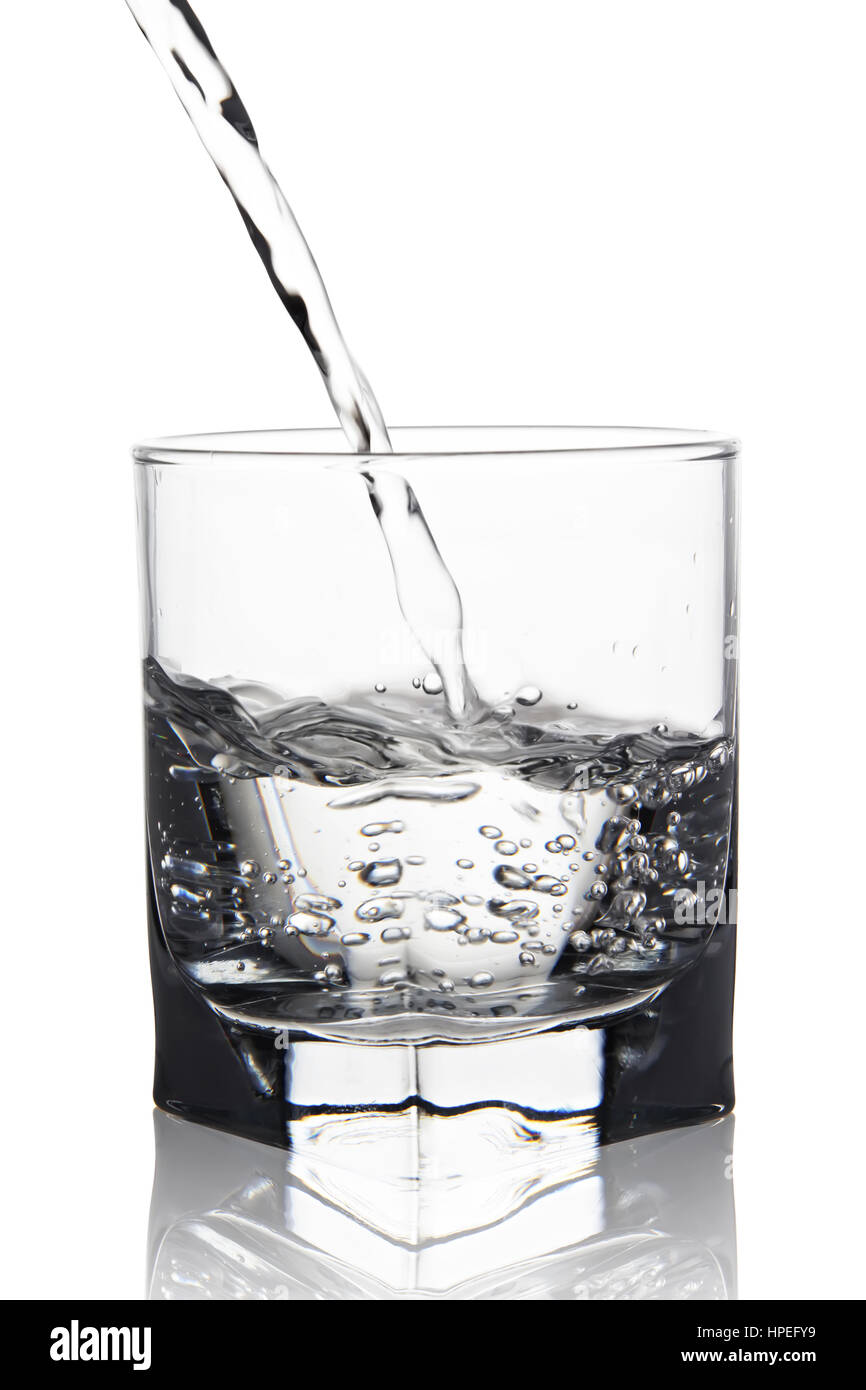 Water with air bubbles pouring into glass with its reflection closeup ...