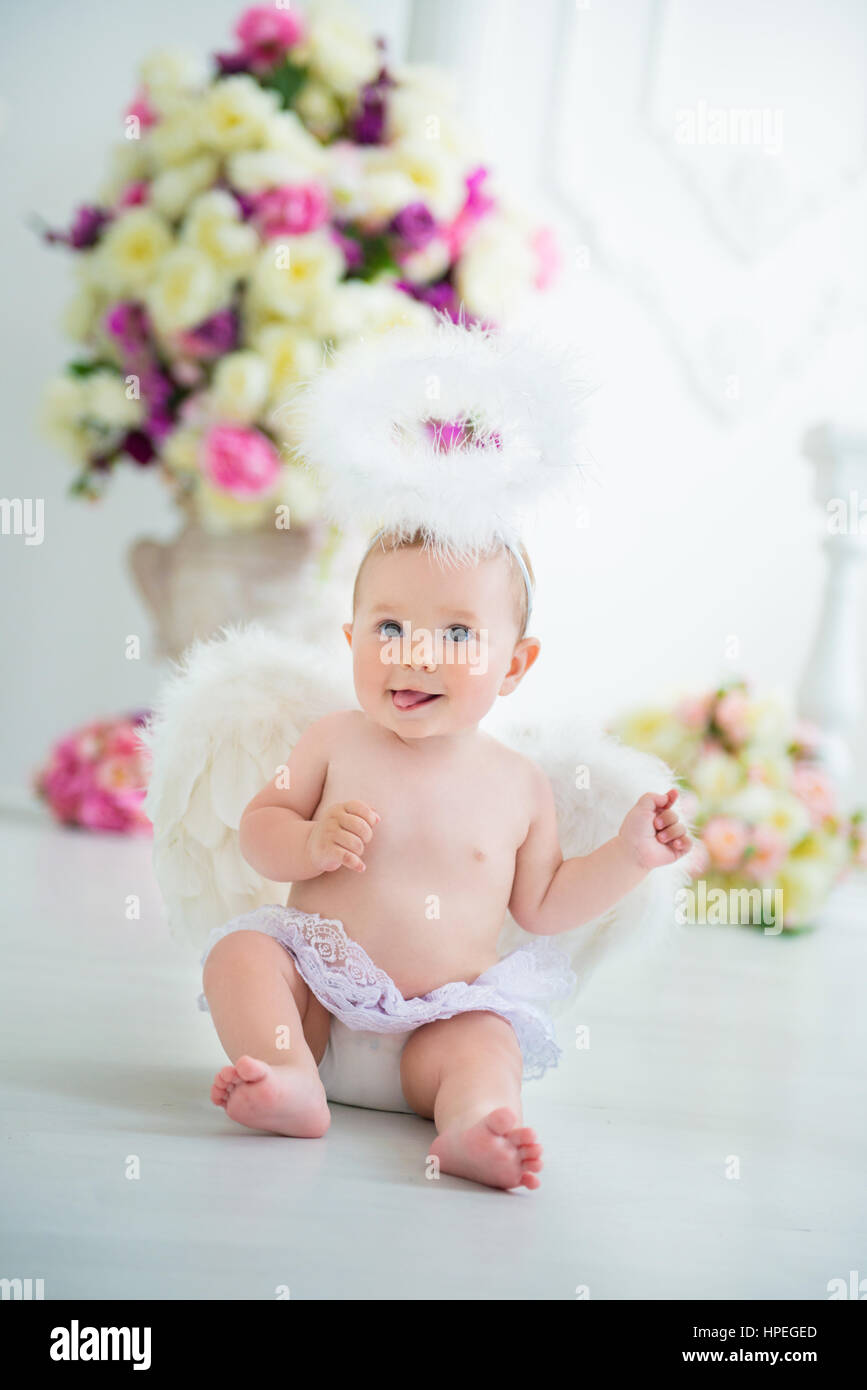 Little angel smiling and happy sitting on the background of flowers and ...