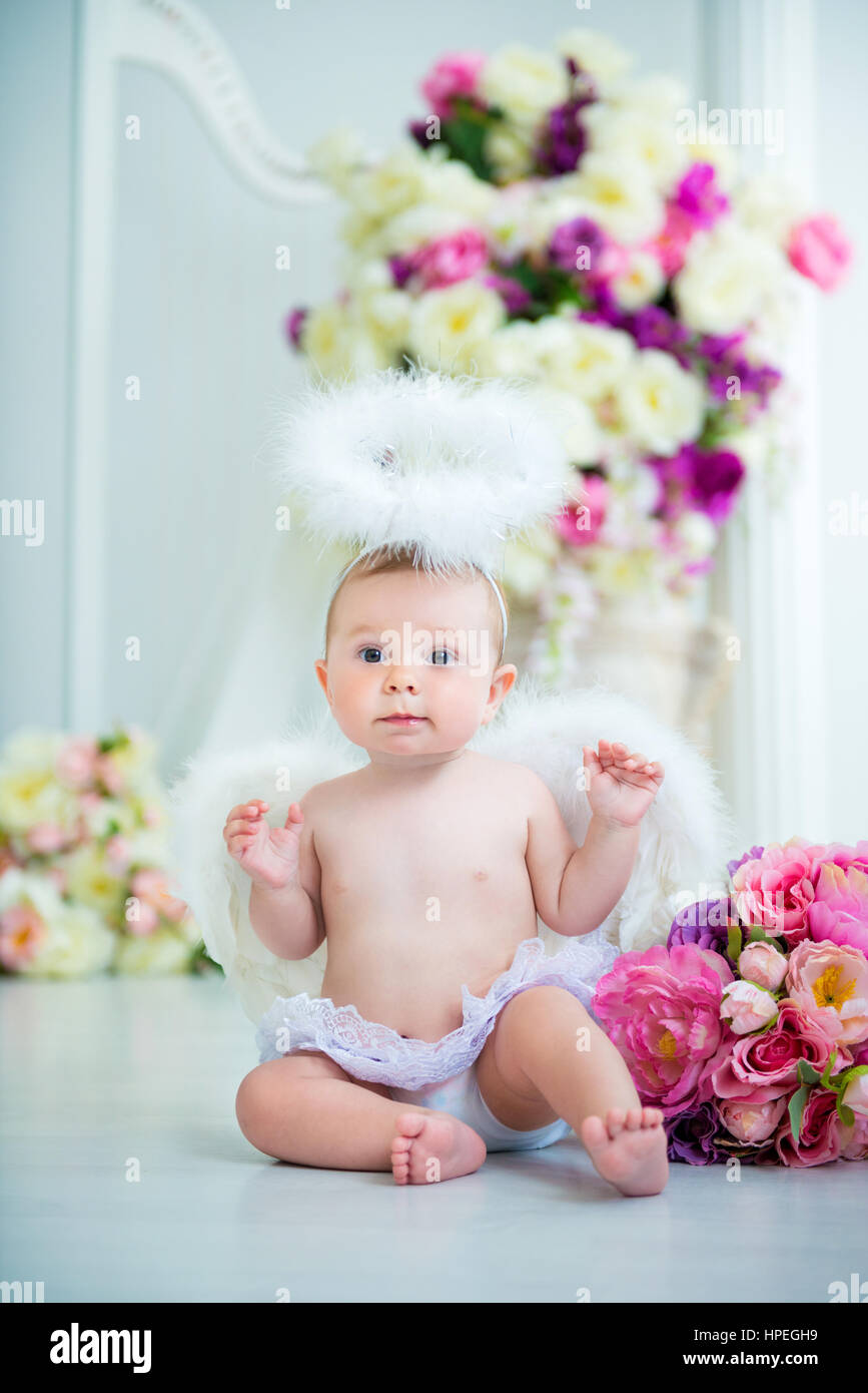 Little angel smiling and happy sitting on the background of flowers and ...