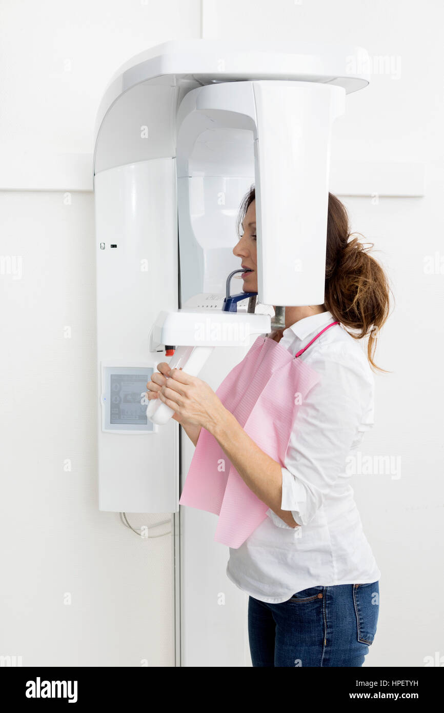 Side view of female patient using digital panoramic xray machine in ...