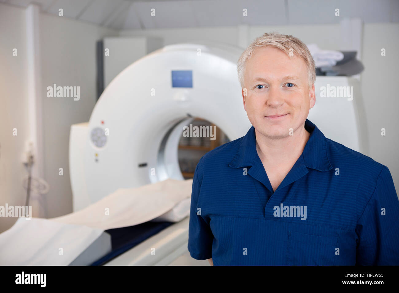 Smiling male professional standing by MRI machine in hospital Stock ...