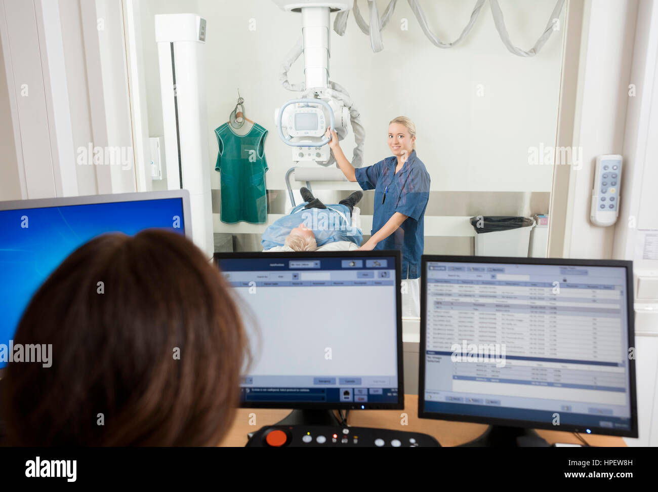 Female radiologist taking patient's xray while colleague using ...