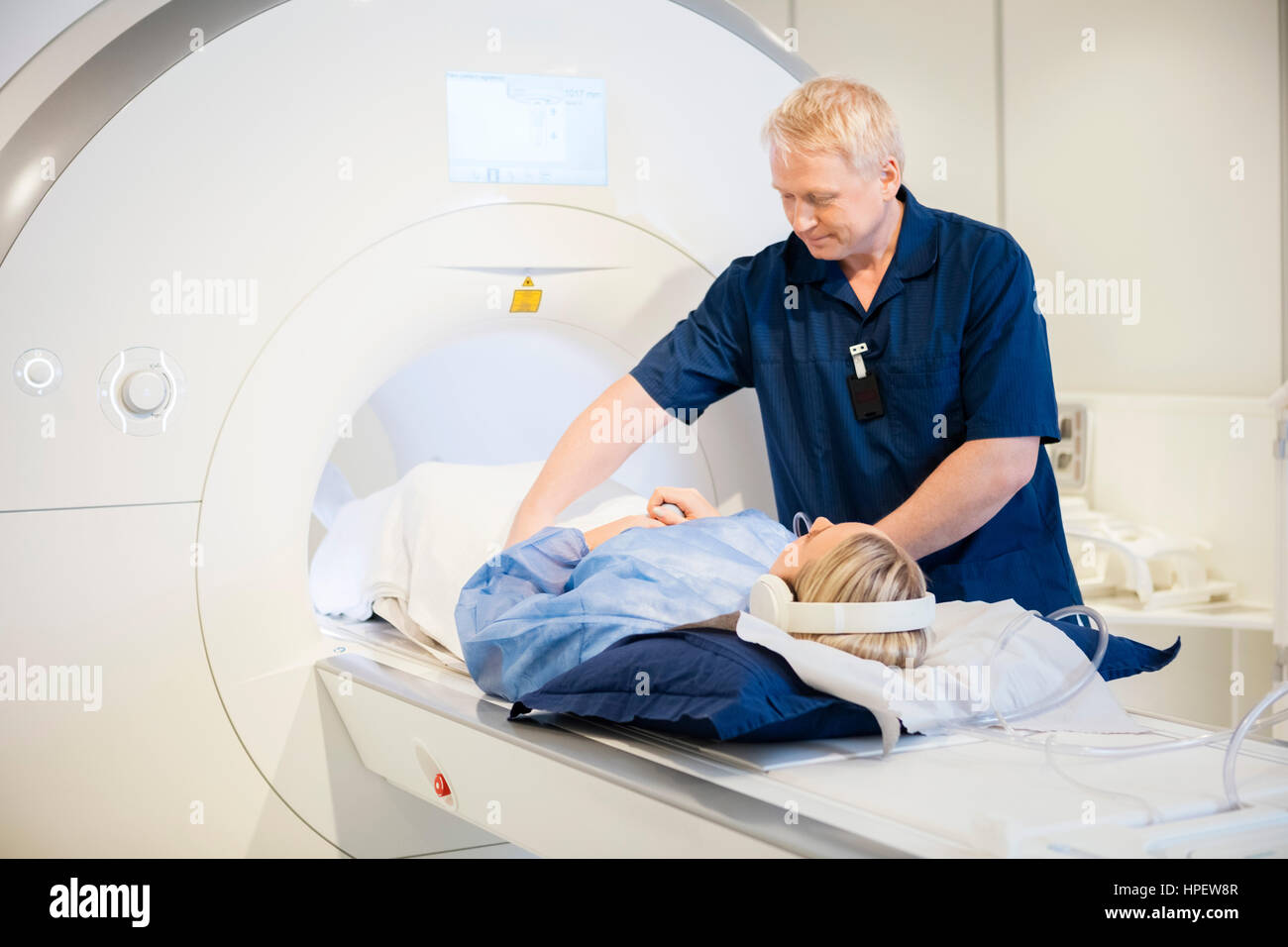 Mature male radiologist preparing woman for MRI scan in laboratory ...