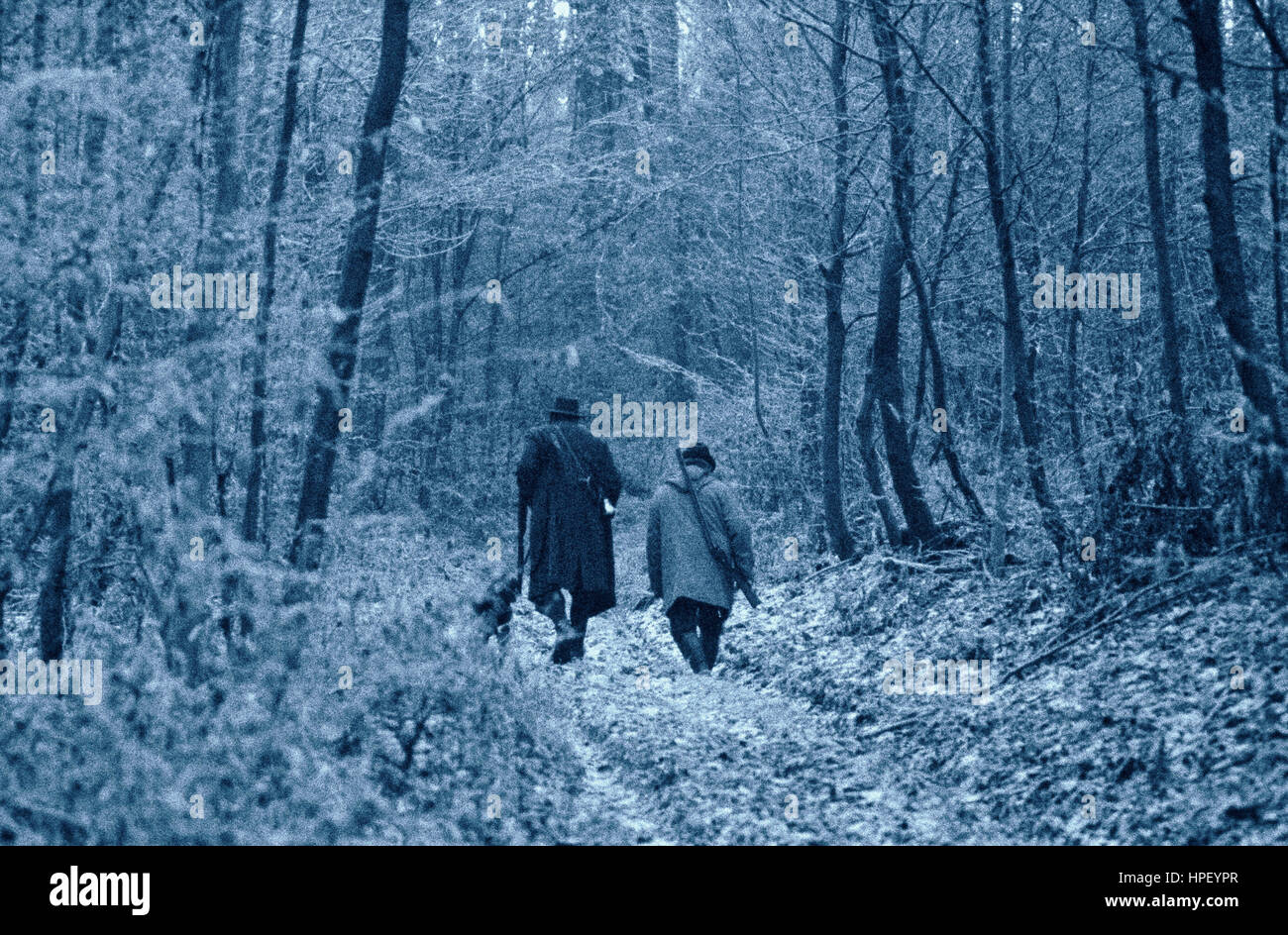 two hunters running on a way through the snowy forest in the winter ...