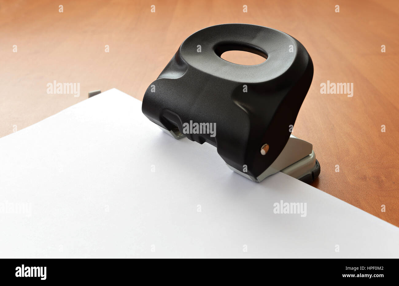 Hole puncher with paper on wood office table Stock Photo - Alamy