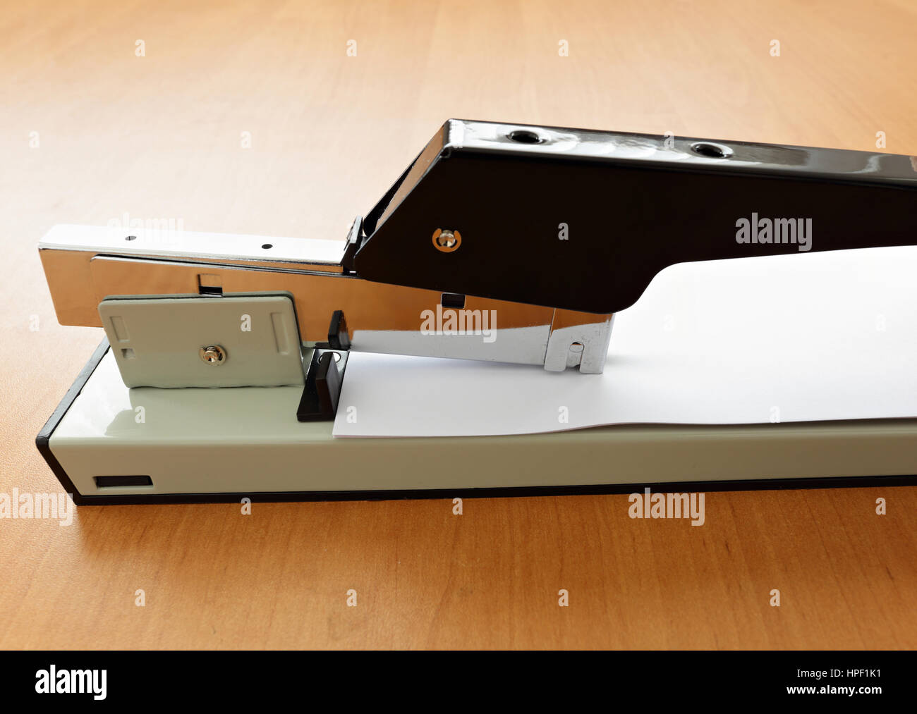 Stapler in progress stapling paper on wood table Stock Photo - Alamy