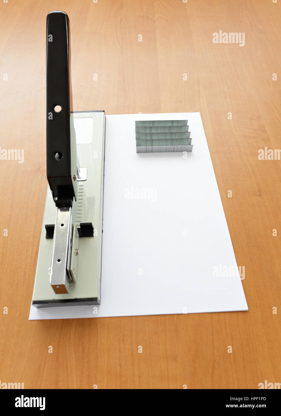 Stapler and staples with paper on wood table Stock Photo - Alamy