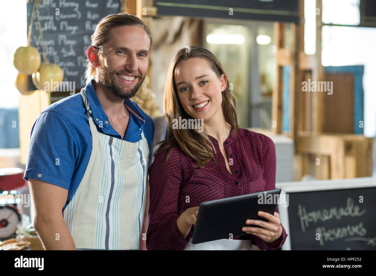 Portrait of smiling bakery staff using digital tablet at counter in ...
