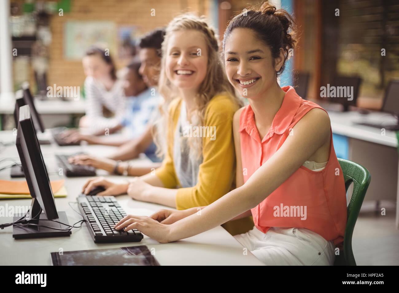 Portrait of smiling students studying in computer classroom at school ...