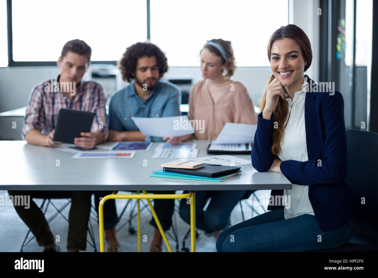Portrait of smiling female business executive sitting at desk and ...