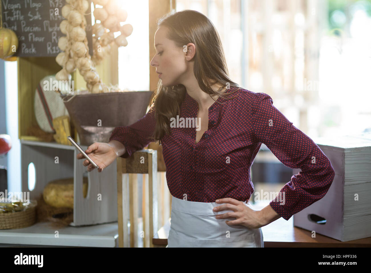 Female staff using mobile phone at counter in bake shop Stock Photo - Alamy
