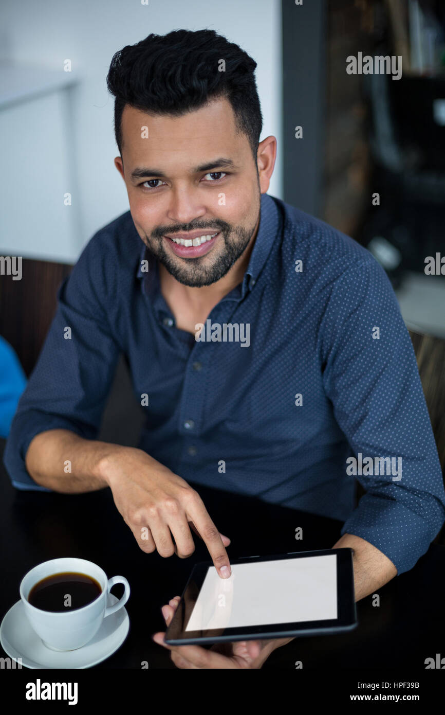 Portrait of smiling business executive using digital tablet while ...
