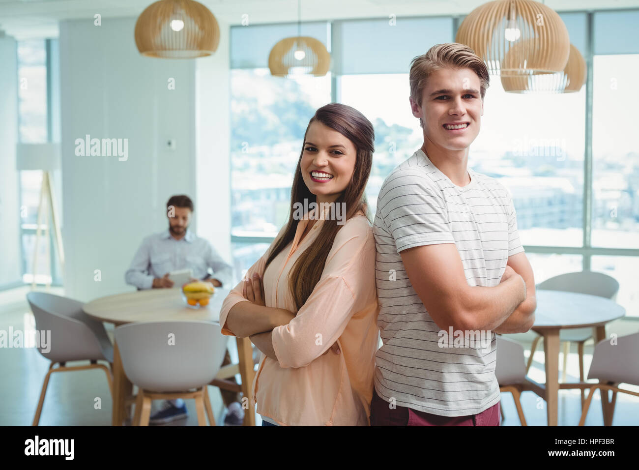 Portrait of happy business executives standing back to back in office ...