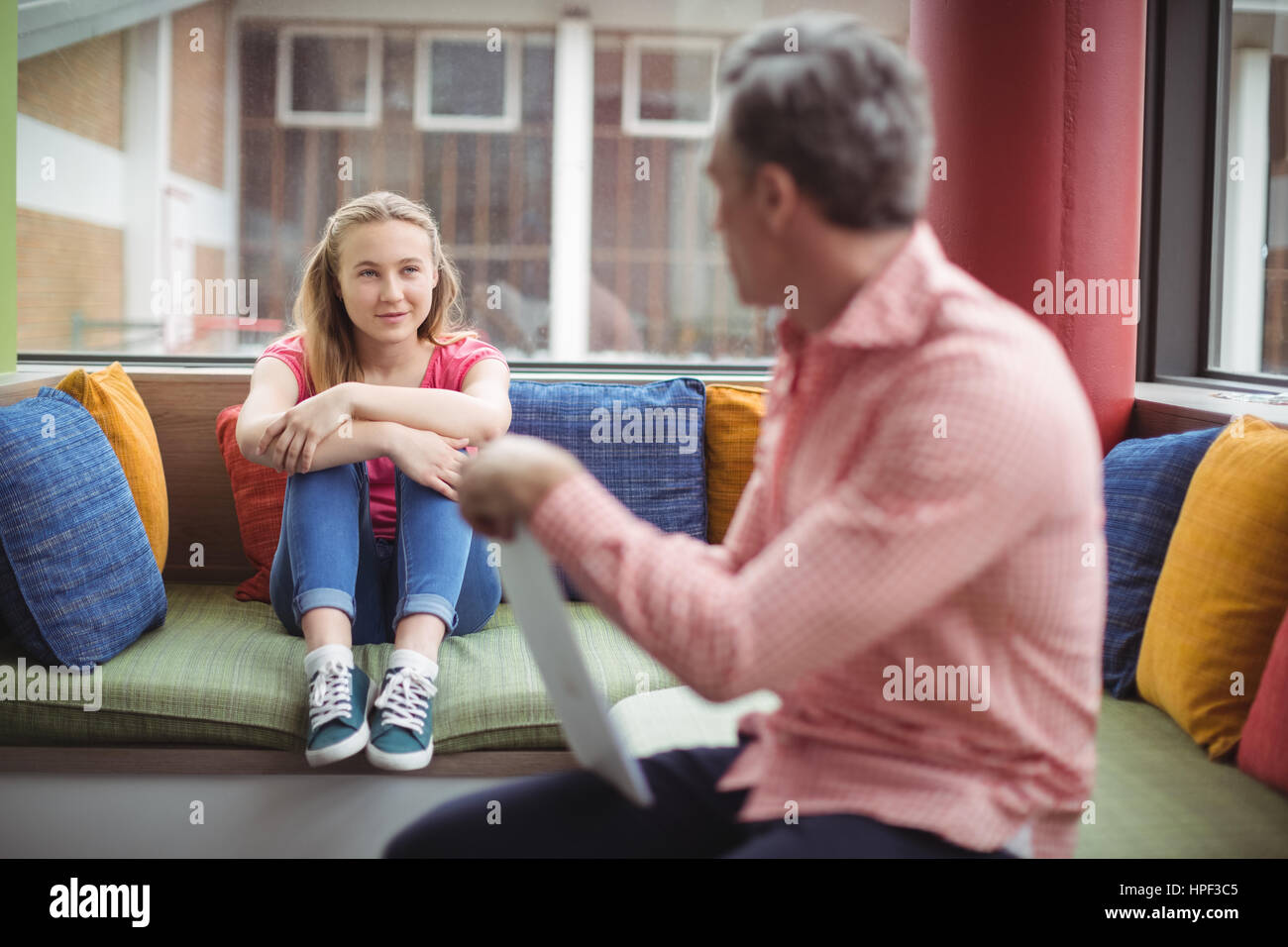 Teacher interacting with student in library at school Stock Photo - Alamy