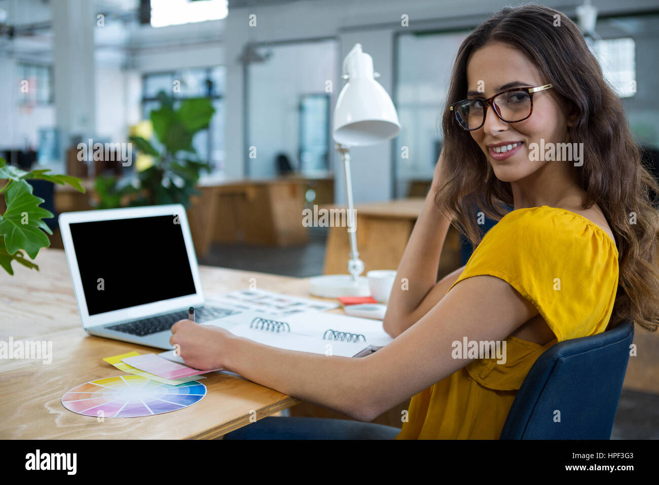 Portrait of a female graphic designer working at desk in creative ...