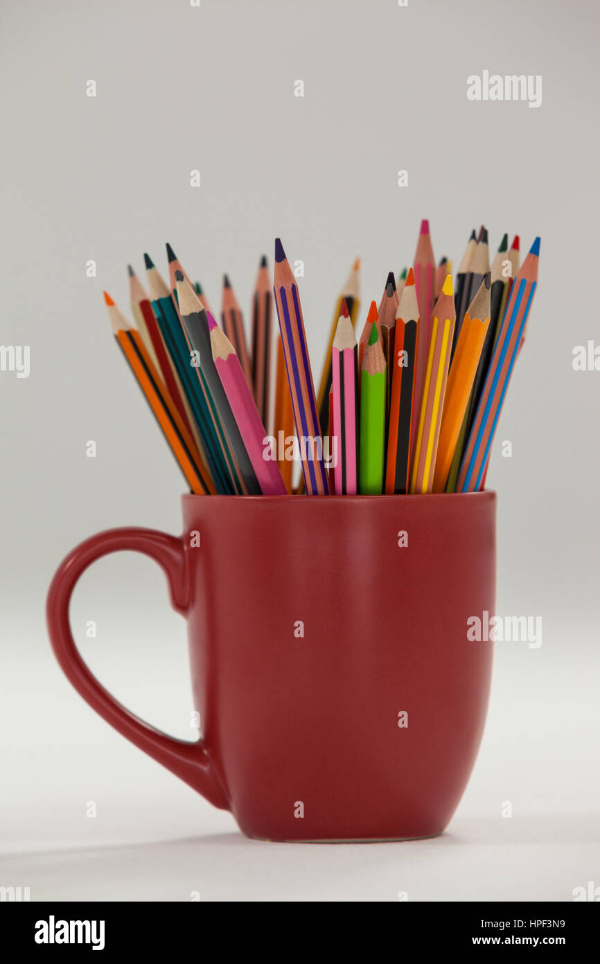 Colored pencils kept in cup on white background Stock Photo - Alamy