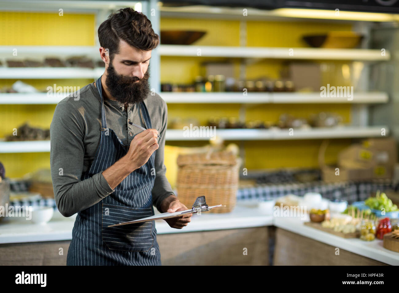 Salesman holding clipboard at counter in grocery shop Stock Photo - Alamy