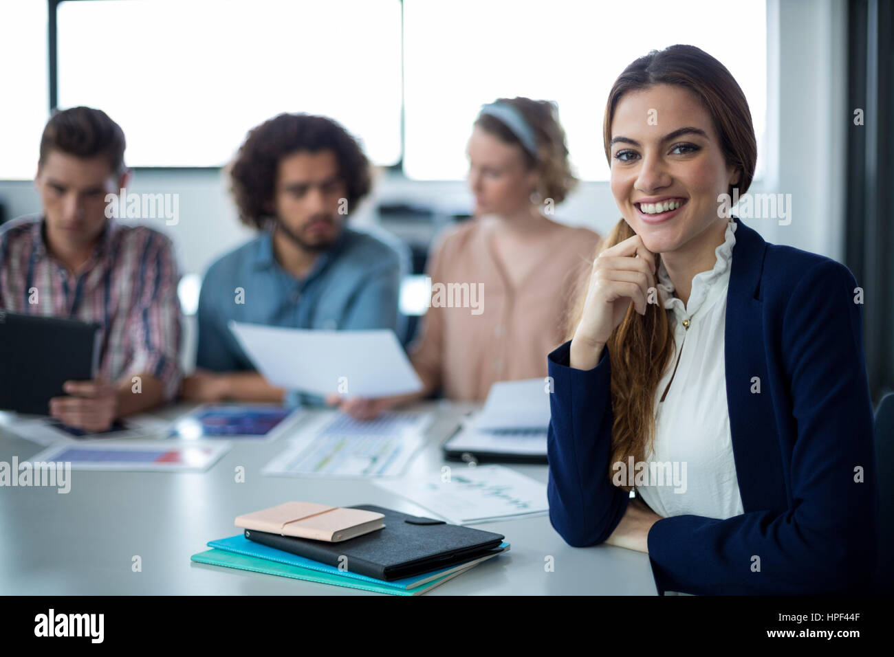 Portrait of smiling female business executive sitting at desk and ...