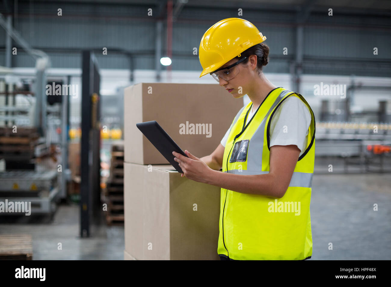 Attentive female factory worker using a digital tablet in factory Stock ...