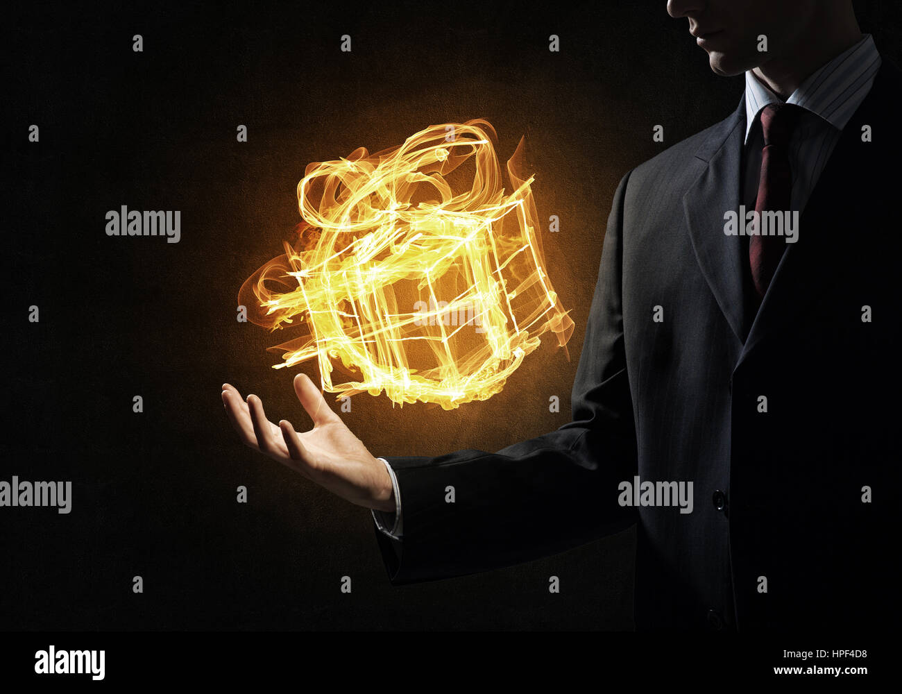 Glowing fire gift box icon in palm on dark background Stock Photo - Alamy