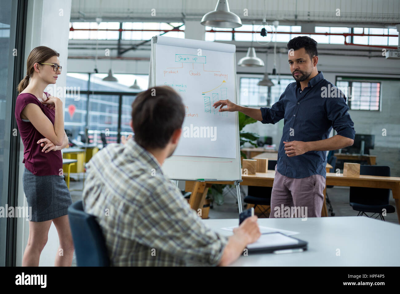 Business executives discussing over flip chart during meeting in office ...
