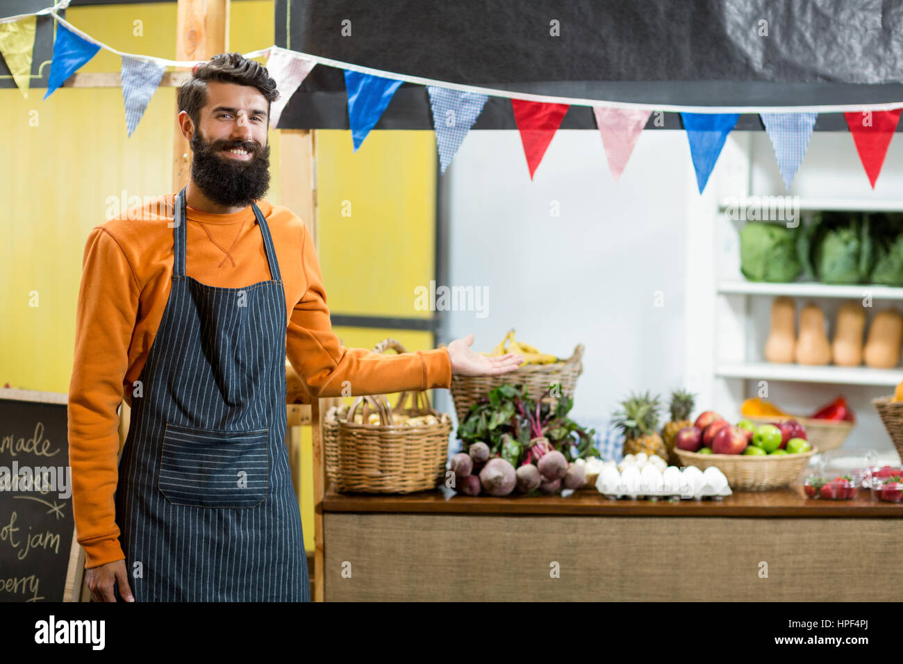 Portrait of a vendor pointing towards counter in grocery store Stock ...