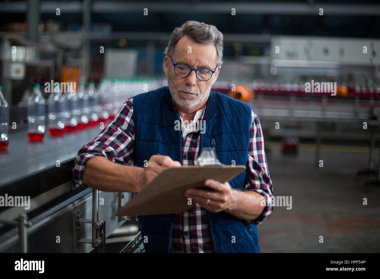 Male factory worker maintaining record on clipboard in drinks ...