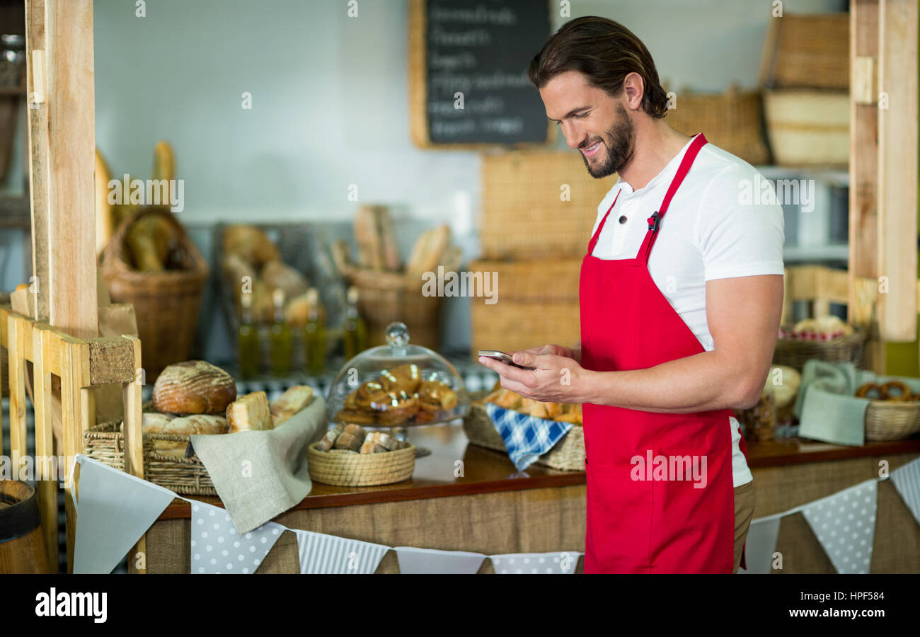 Smiling bakery staff using mobile phone at counter in bake shop Stock ...
