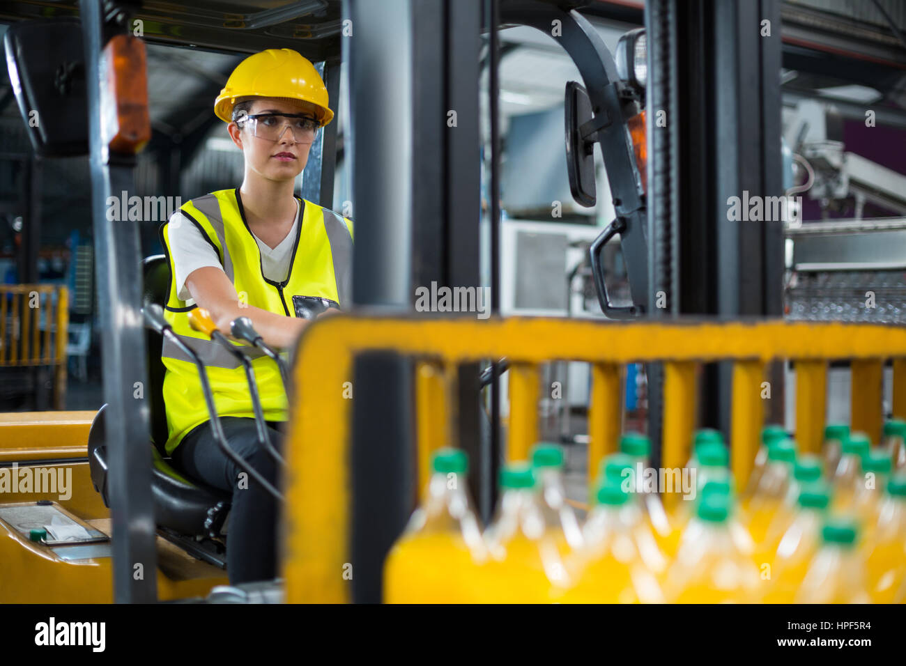 Attentive female factory worker driving forklift in factory Stock Photo ...