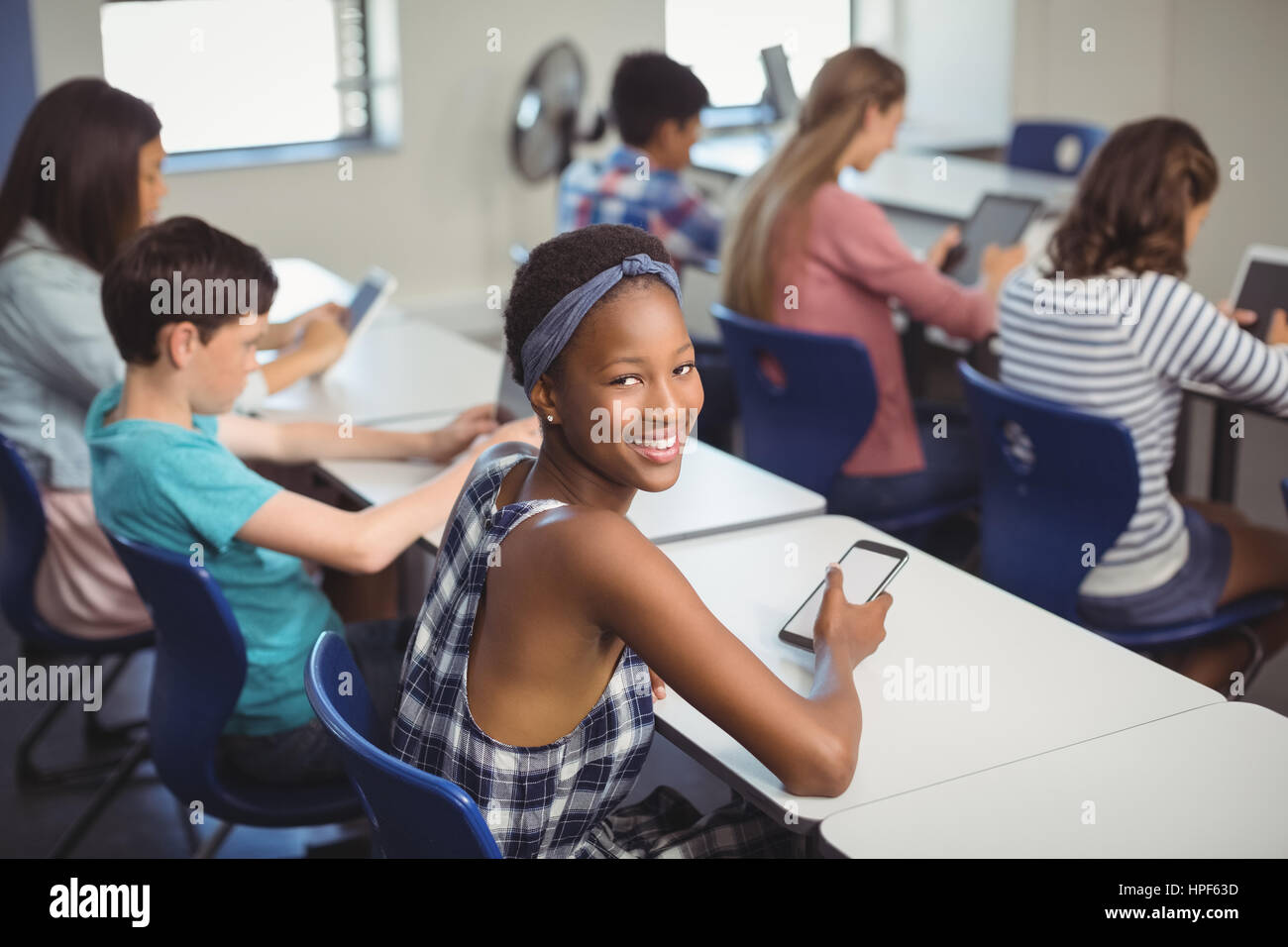 Portrait of student holding mobile phone in classroom at school Stock ...