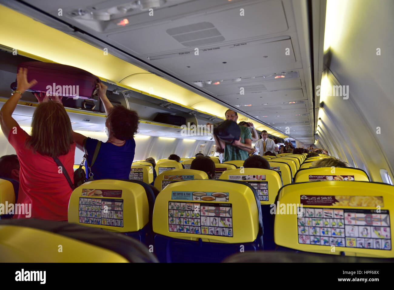 Passengers inside airplane loading bags into overhead locker Stock ...