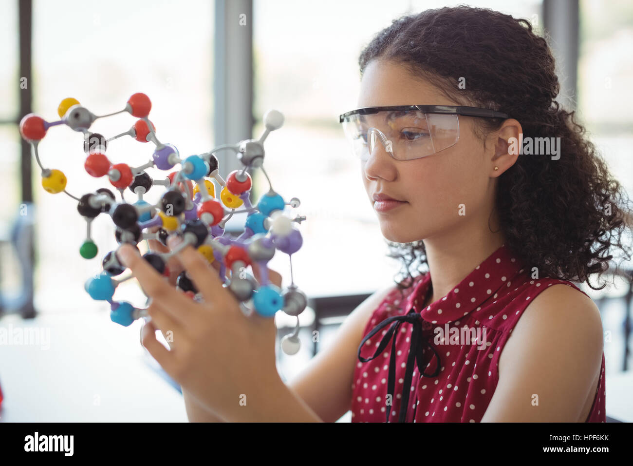 Attentive schoolgirl experimenting molecule model in laboratory at ...