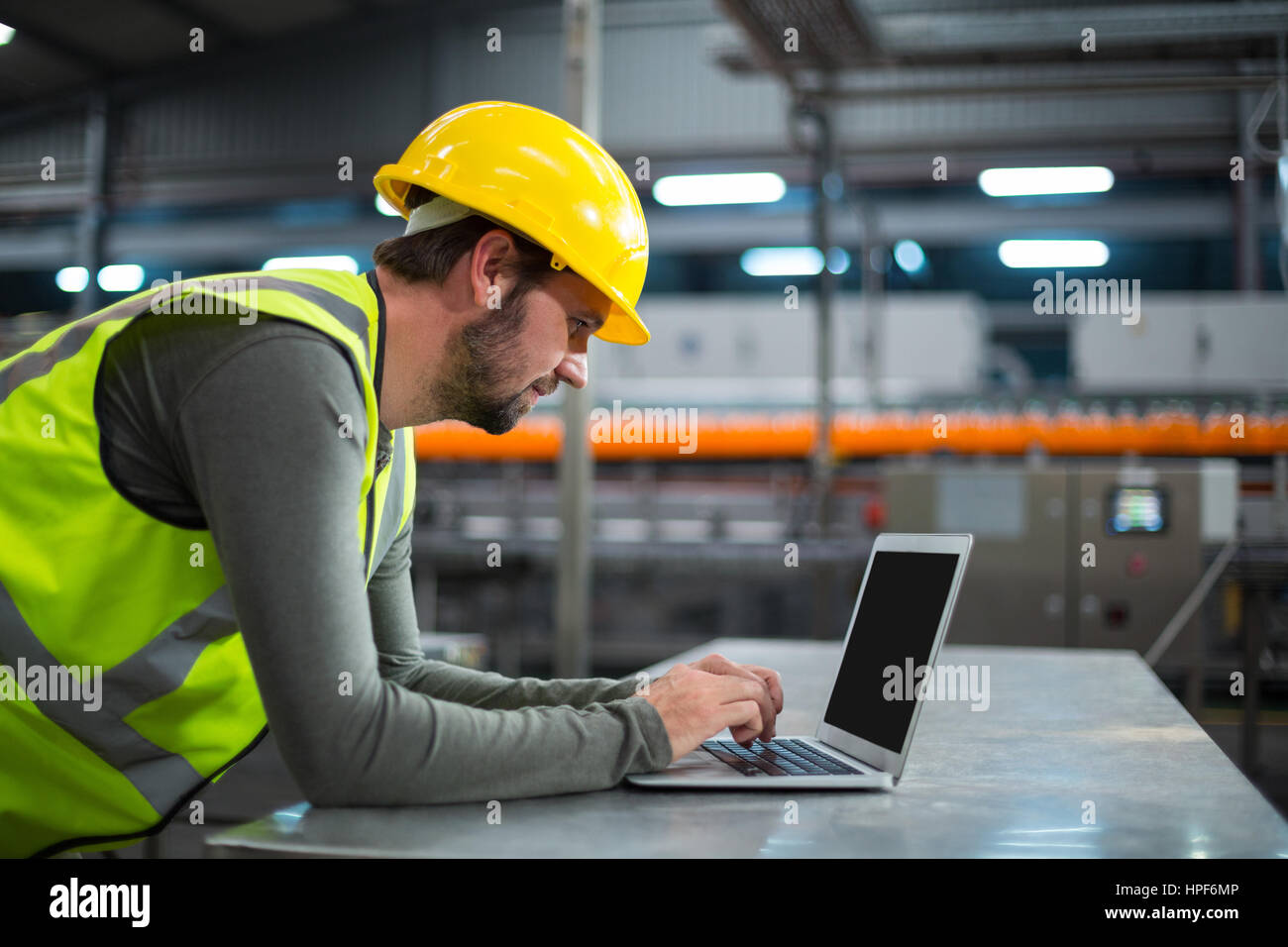 Factory worker using laptop at drinks production factory Stock Photo ...