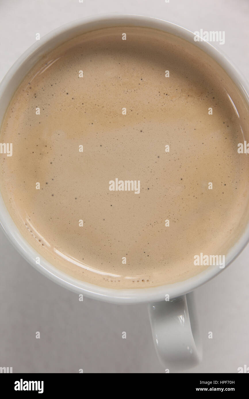 Close-up of white coffee cup with creamy froth on white background ...