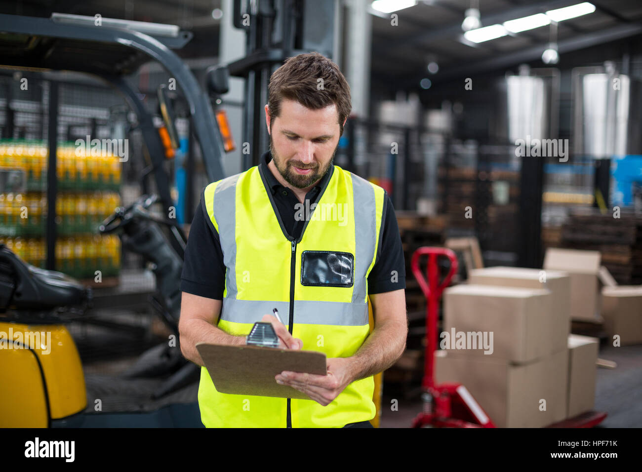 Attentive factory worker writing on clipboard in factory Stock Photo ...