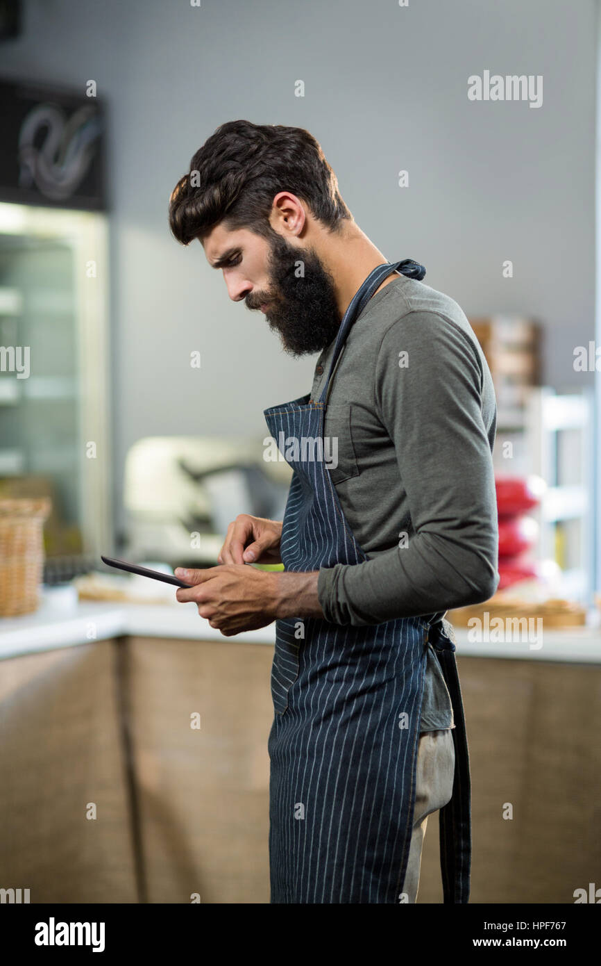 Salesman using digital tablet at counter in grocery shop Stock Photo ...