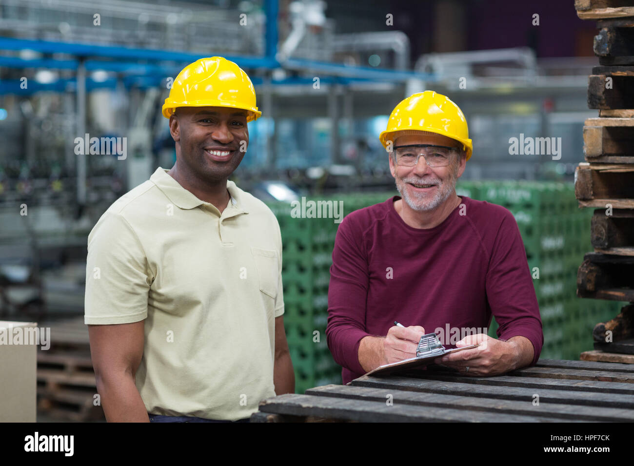 Portrait of two factory workers standing with clipboard in drinks ...