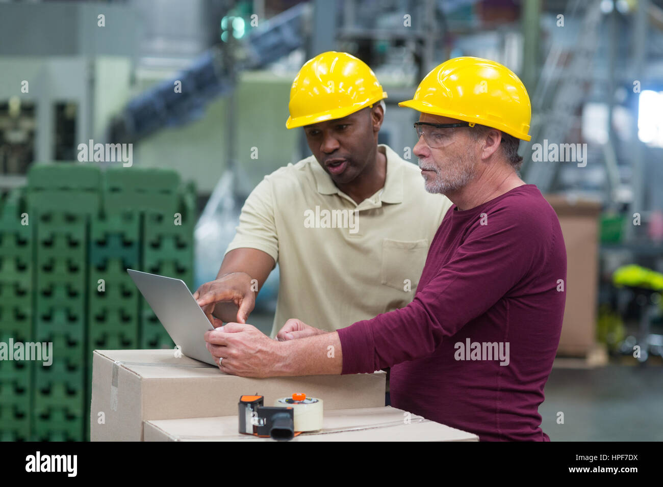 Two factory workers discussing while working on laptop in drinks ...