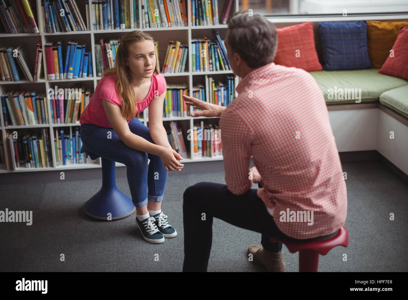 Teacher interacting with student in library at school Stock Photo - Alamy