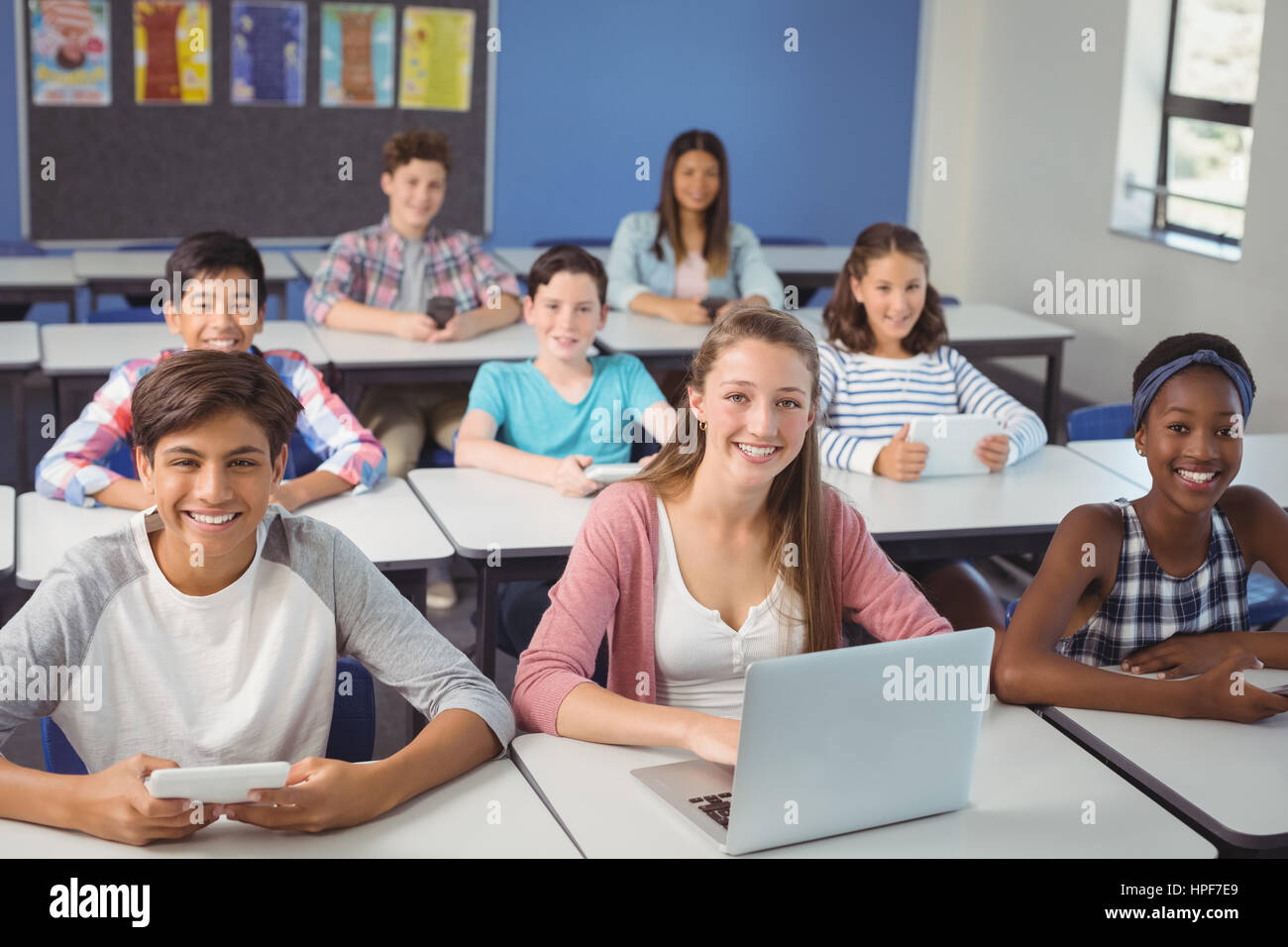 Portrait of students with digital tablet and laptop in classroom at ...