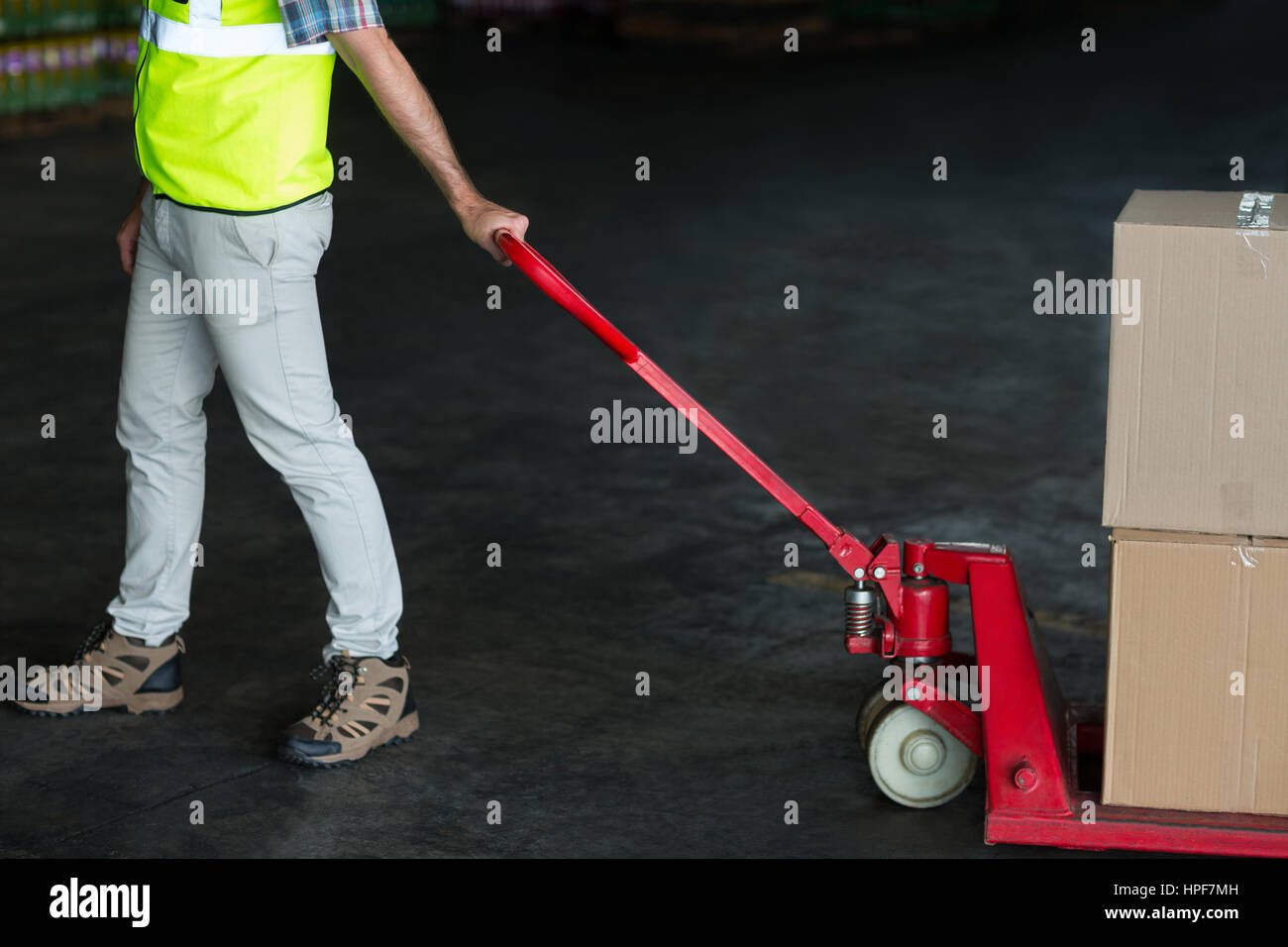 Factory worker pulling trolley of cardboard boxes in factory Stock ...