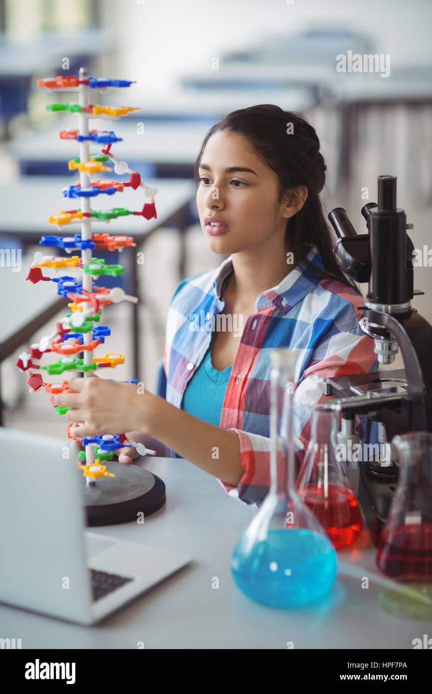 Attentive schoolgirl experimenting molecule model in laboratory at ...